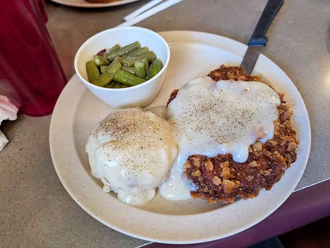Behold the star attraction: chicken fried steak smothered in peppery gravy with a side of green beans—a plate that whispers "Nebraska" with every bite.