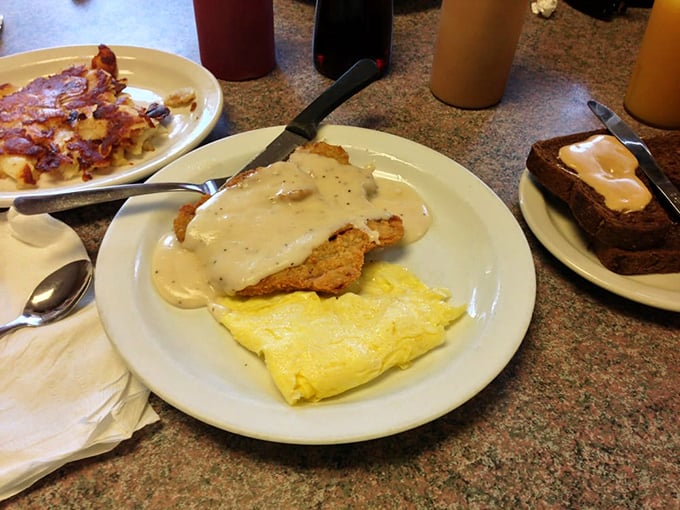 Behold the star attraction! Golden-crisp chicken fried steak smothered in peppery gravy alongside fluffy eggs—a plate that makes diets weep and souls rejoice.
