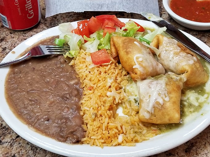 These chimichangas aren't just fried – they're transformed into golden vessels of joy, accompanied by the holy trinity of Mexican sides: rice, beans, and fresh garnish.