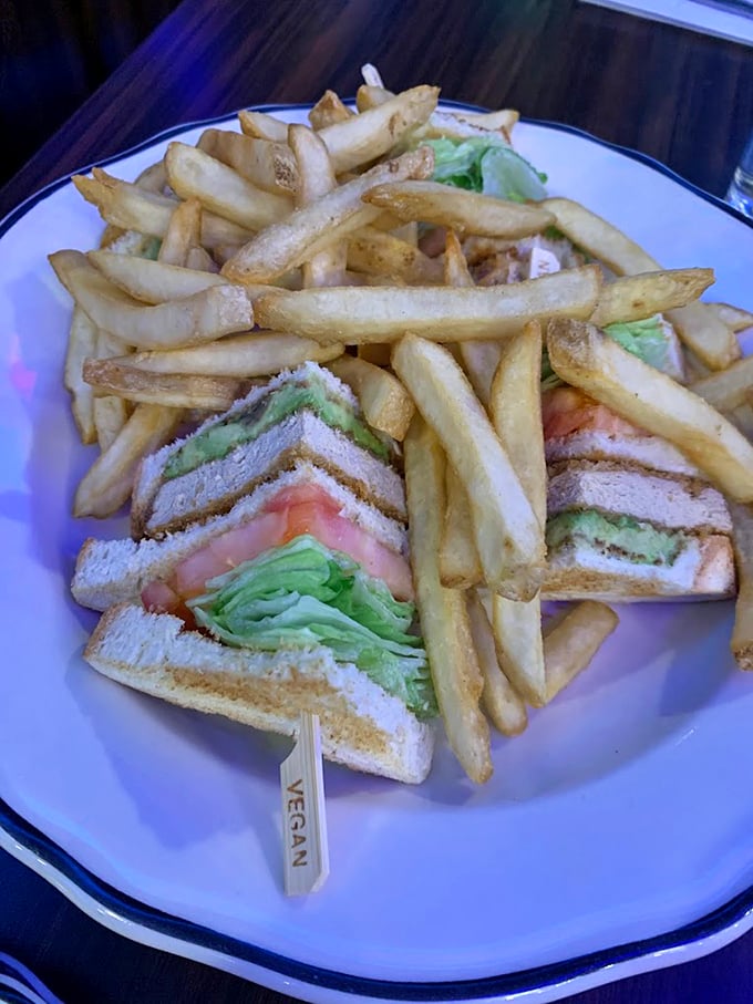 The club sandwich arrives like architecture on a plate—perfectly toasted bread, real turkey, and enough bacon to make any day better.