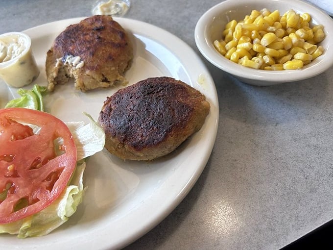 Behold the stars of the show—crab cakes with minimal filler and maximum flavor, perfectly browned and served with corn that's sweeter than a love letter.