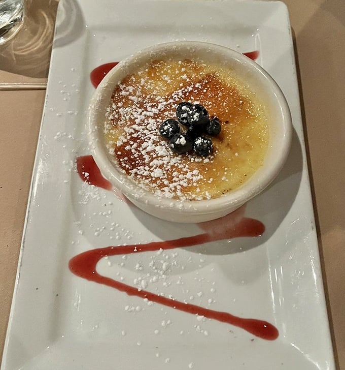 Crème brûlée that cracks like thin ice on a winter pond, topped with plump blueberries and a raspberry coulis signature.
