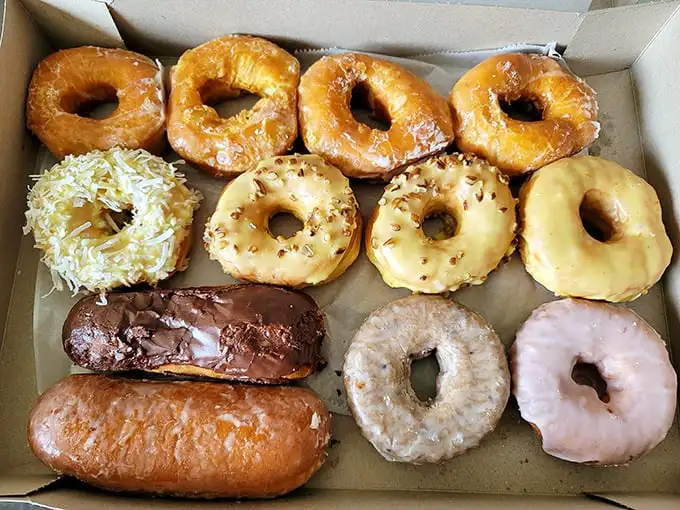A dozen reasons to break your diet, arranged like edible jewelry in a cardboard treasure chest. The chocolate long john alone could feed a small family.