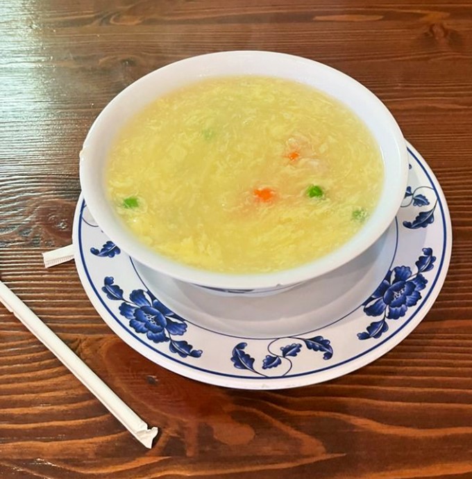 This isn't just egg flower soup—it's liquid comfort in a blue-rimmed bowl. Delicate egg wisps float like golden clouds in a broth that's clearer than your grandmother's advice.