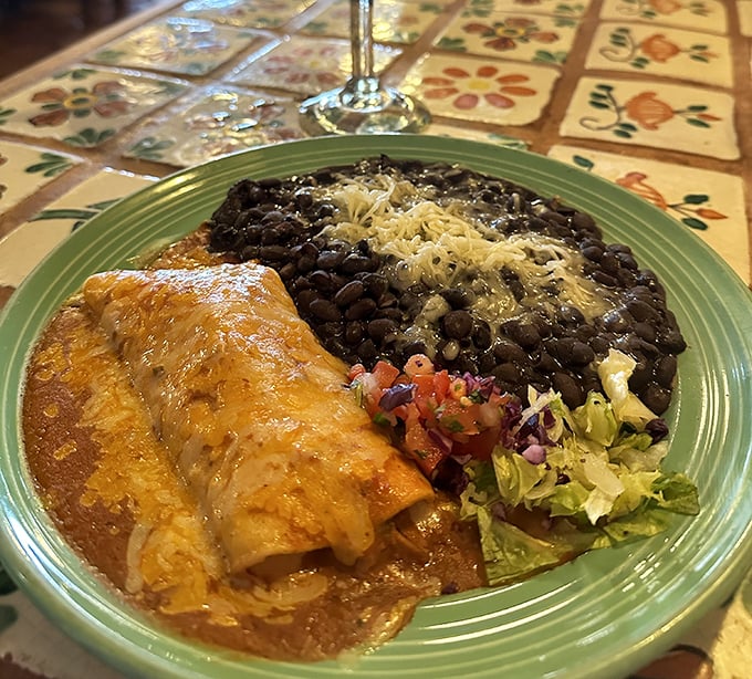 This isn't just an enchilada – it's a masterclass in comfort food, nestled beside black beans that could make a convert of any legume skeptic.