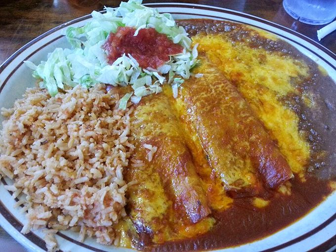 These enchiladas aren't just served—they're presented with pride, swimming in rich sauce alongside perfectly executed rice and beans.