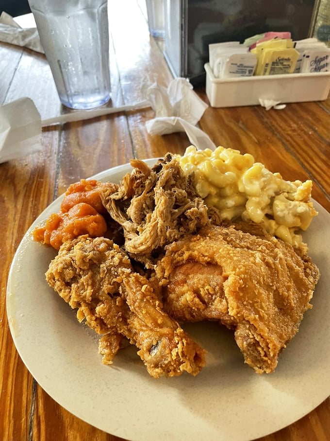 Golden-crusted fried chicken alongside creamy mac and cheese and sweet yams – the holy trinity of Southern comfort on a single plate.