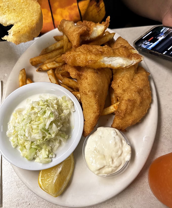 The star attraction arrives: golden-battered fish with a perfect crunch, accompanied by crisp fries, house-made coleslaw, and that all-important tartar sauce.