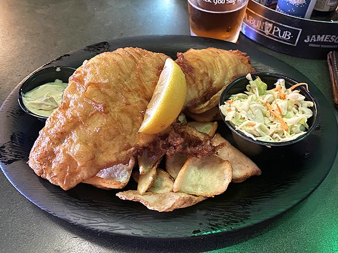 Golden, crispy batter shatters like delicate glass around tender haddock, while a lemon wedge stands ready to cut through the richness – fish and chips perfection.