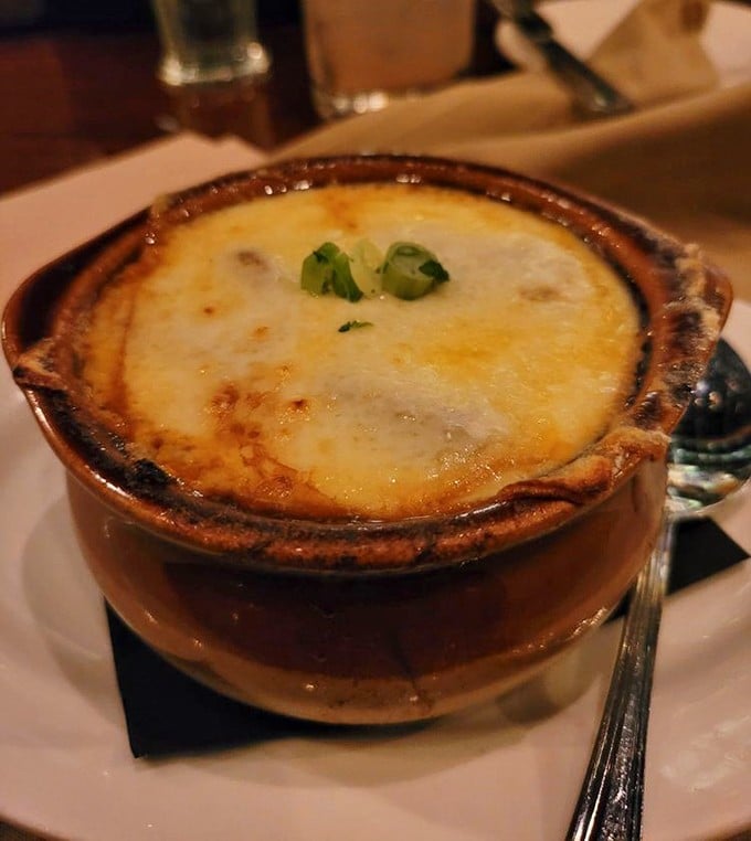 Behold the French onion soup in all its glory—a bubbling cauldron of cheese-capped perfection that would make Julia Child weep with joy.
