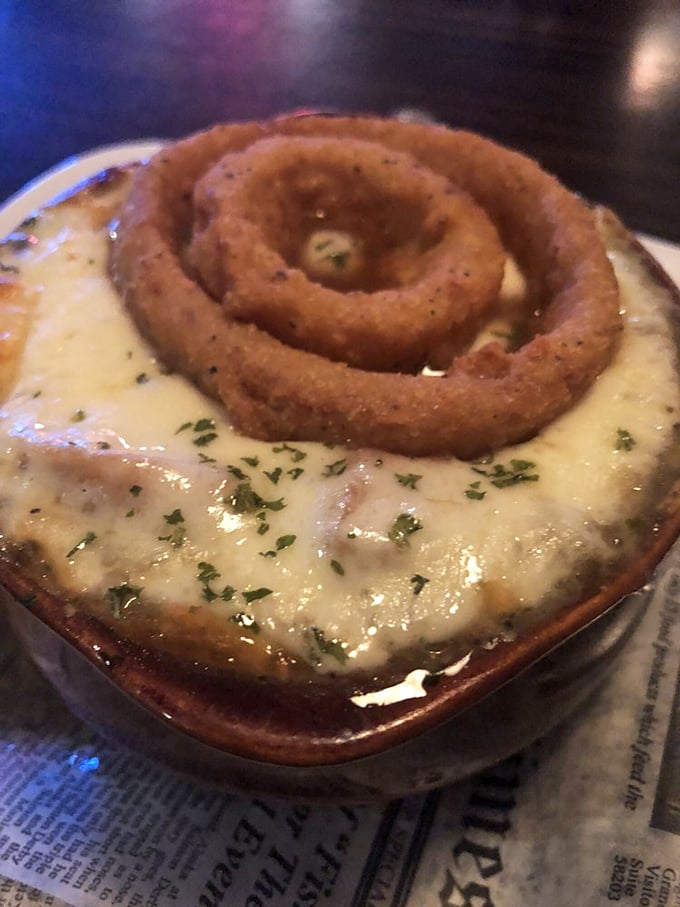 The legendary French onion soup arrives crowned with a perfect onion ring and blanketed in melted cheese that stretches with each spoonful—comfort in a crock.