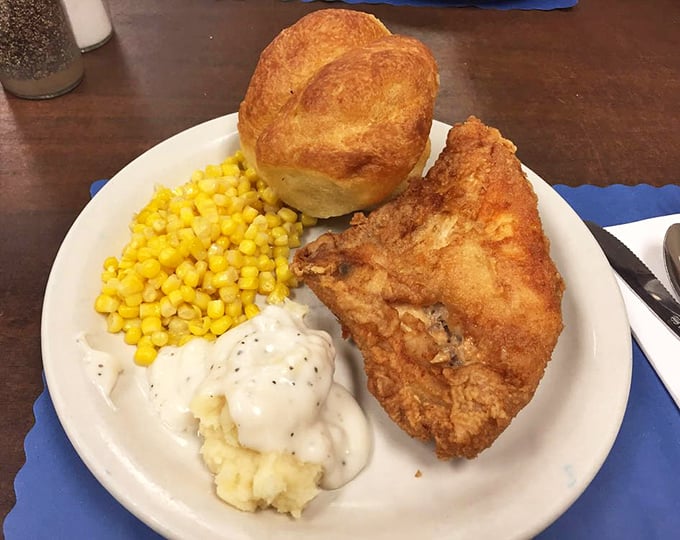 The holy trinity of comfort food: golden fried chicken, creamy mashed potatoes with gravy, and sweet corn—plus a roll that's begging to be buttered.