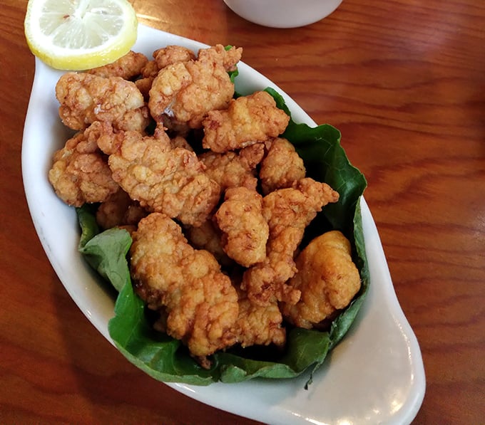 Golden-fried gator tail bites perched on fresh greens – proof that sometimes the predator becomes the most delicious prey.