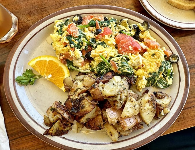 The legendary Greek Scramble in its natural habitat—bright yellow eggs mingling with spinach and feta, while those home fries play the perfect supporting role.