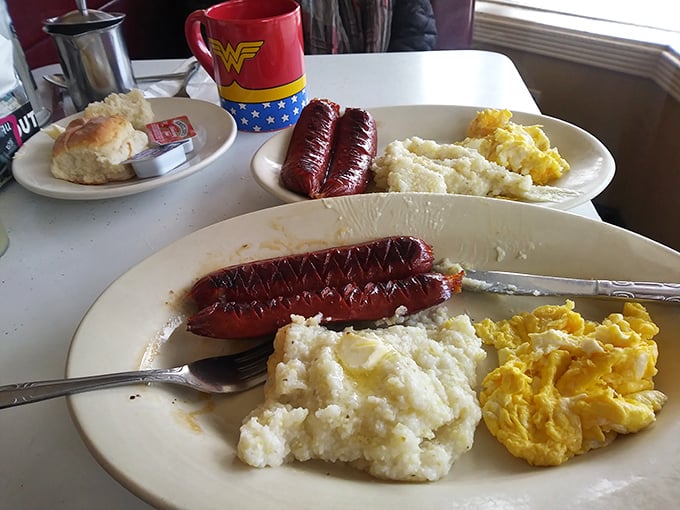 Sausage links with grits and eggs—a breakfast trinity that proves some culinary equations need no solving. That Wonder Woman mug isn't just for show.