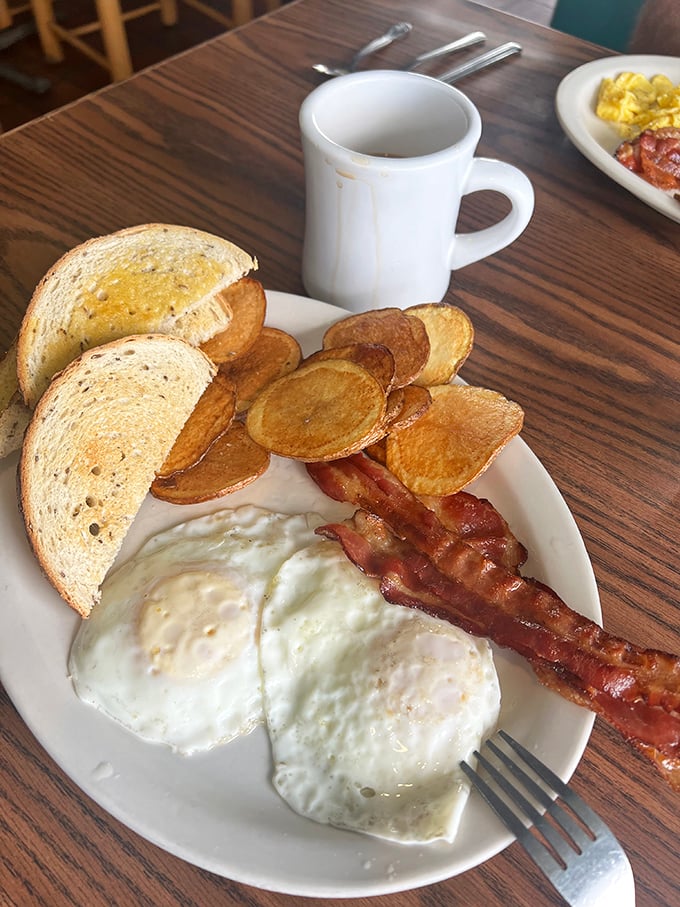 Sunny-side up eggs, perfectly crisped bacon, and golden home fries—the holy trinity of breakfast done right, no Instagram filter required.