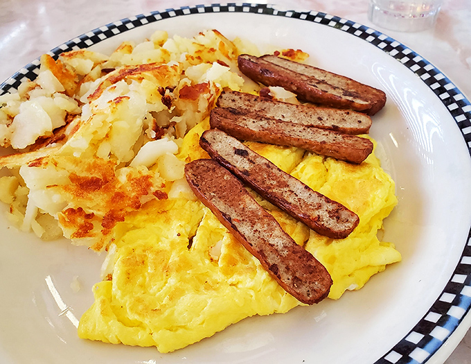 Sunshine on a plate: perfectly scrambled eggs, crispy home fries, and sausage links that snap with each bite—the breakfast trifecta.