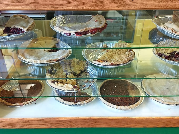 The pie case at Bradley's—where diet plans go to die happy deaths and fruit fillings peek through golden crusts like delicious treasures waiting to be discovered.
