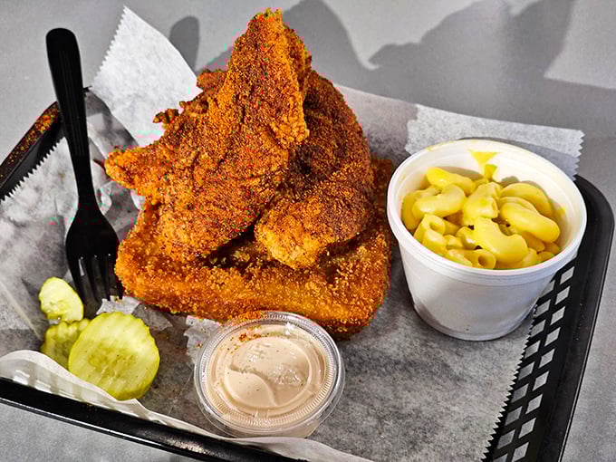 Golden-brown chicken wearing its signature reddish-orange spice coat sits triumphantly beside cooling mac and cheese—a perfect fire-and-rescue combination.