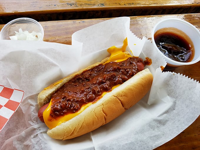 The chili cheese dog in its natural habitat—wrapped in paper, oozing with promise, and demanding a stack of napkins. Worth every messy bite.