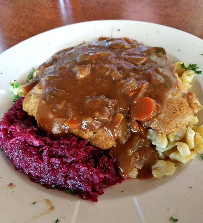 The legendary Jagerschnitzel in its natural habitat – swimming in mushroom gravy alongside vibrant red cabbage that could convert any cabbage skeptic.