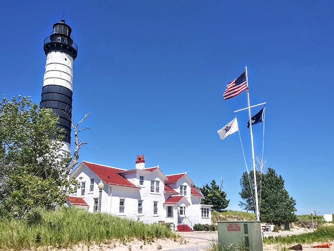 Old Glory waves proudly beside this Great Lakes guardian. The red-roofed keeper's quarters look like they're hosting a perpetual summer barbecue.
