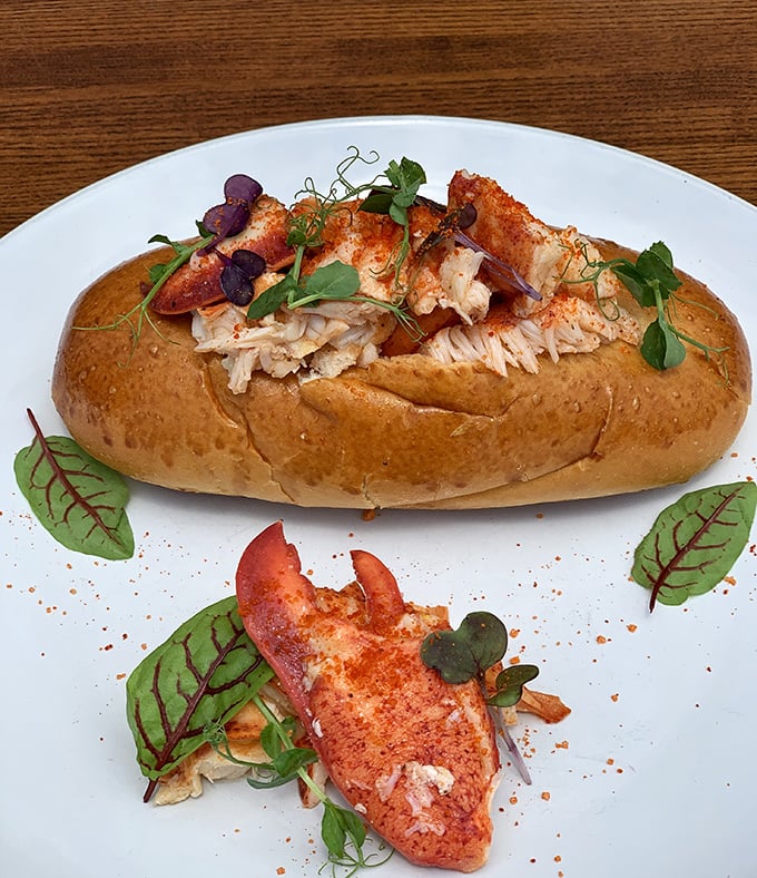 The lobster roll that launched a thousand road trips. Perfectly toasted bun cradling sweet lobster meat, garnished with microgreens – simplicity that speaks volumes about seafood respect.