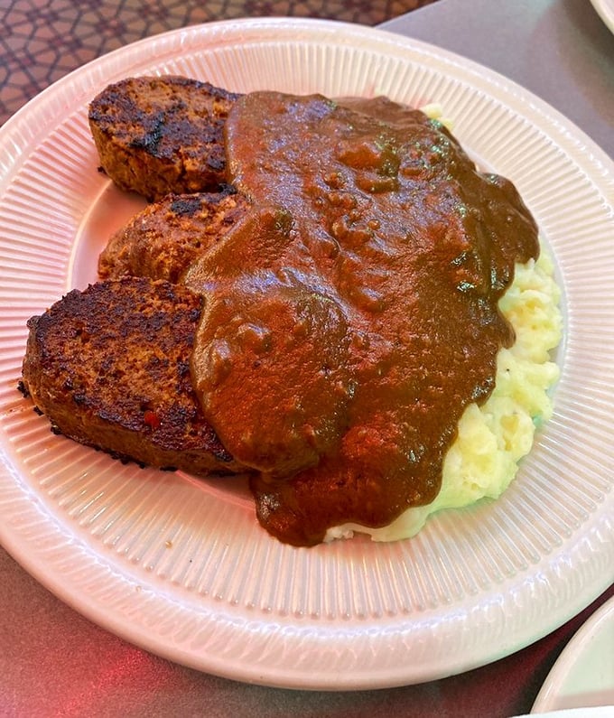 Behold the star attraction: meatloaf that doesn't just sit on the plate—it commands respect, with gravy cascading over mashed potatoes like a savory waterfall.