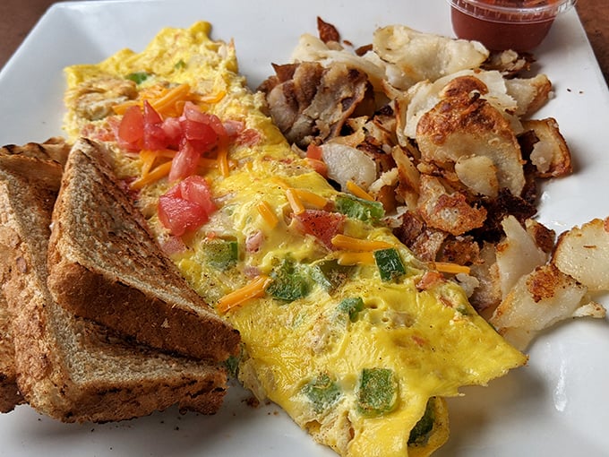 This isn't just an omelet—it's a masterclass in egg architecture, with perfectly crisp home fries standing guard alongside buttery toast soldiers.