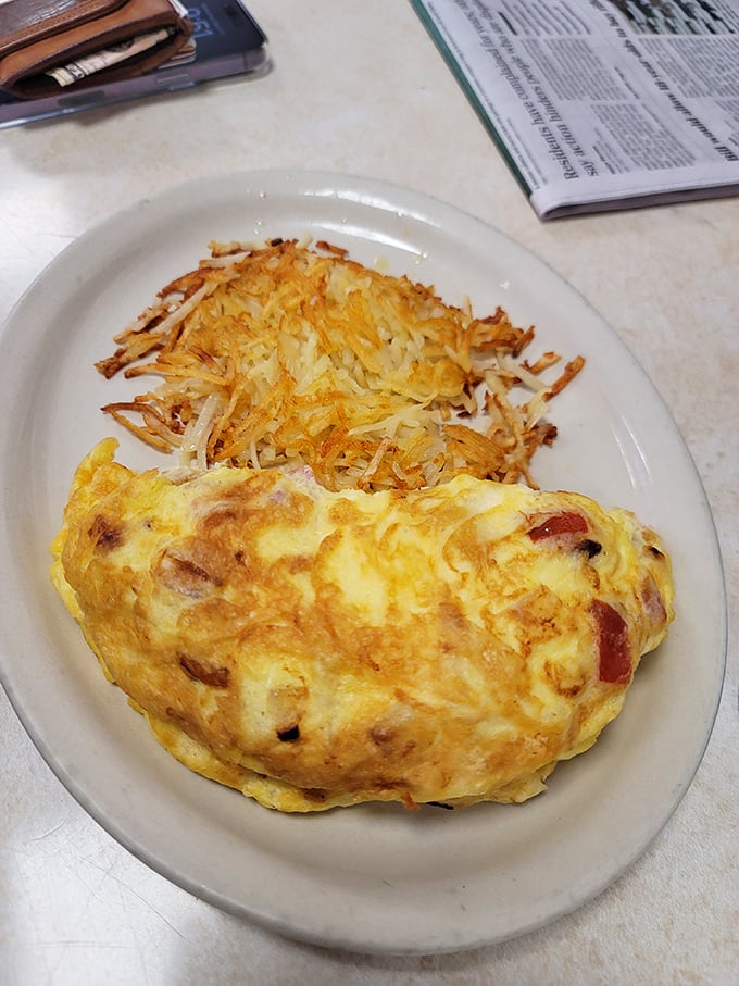 Behold the omelet—a golden pillow of egg perfection nestled against crispy hash browns. Simplicity that somehow manages to be revolutionary.