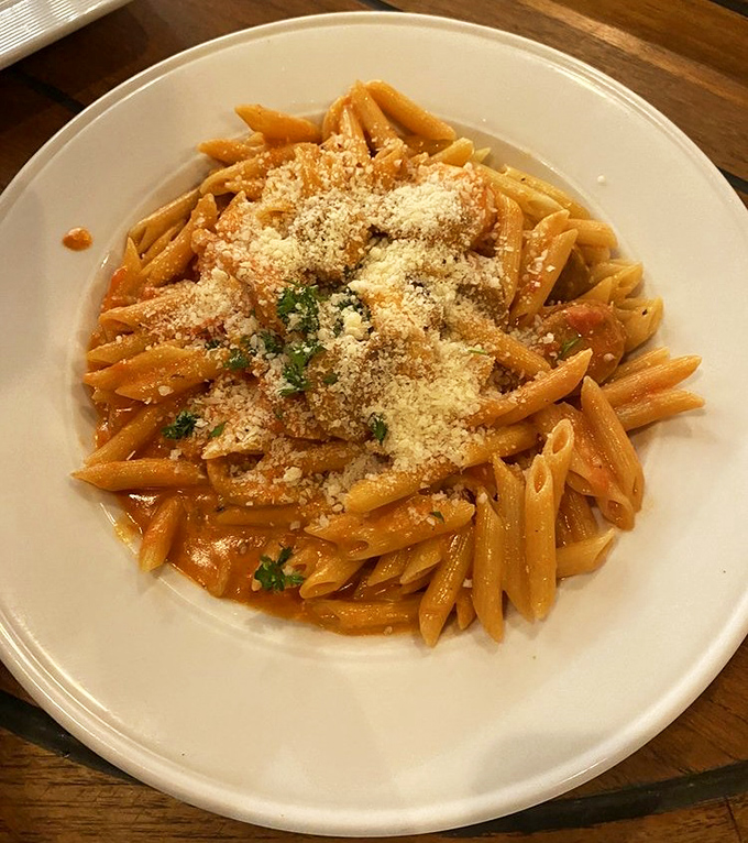 The legendary Penne Rustica arrives like a celebrity—perfectly al dente tubes bathed in a rich tomato sauce, crowned with a snowfall of Parmesan and fresh herbs.