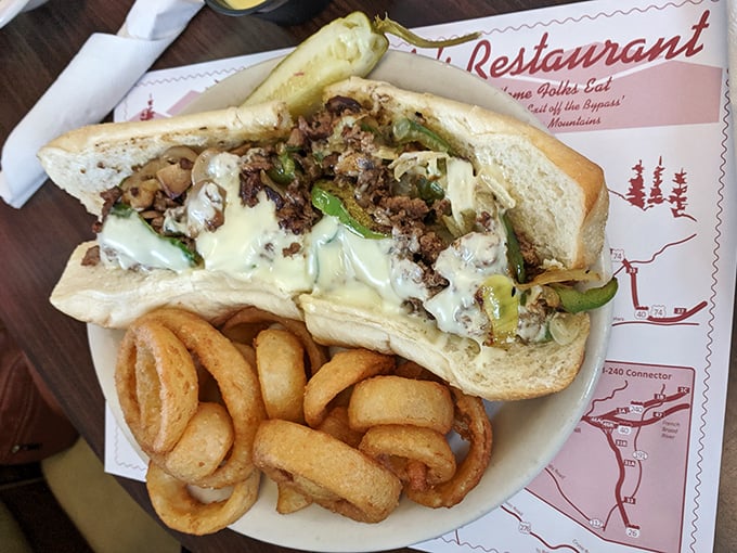 Behold the star attraction – Clyde's legendary Philly cheesesteak with perfectly caramelized onions and peppers, served with crispy onion rings that deserve their own fan club.