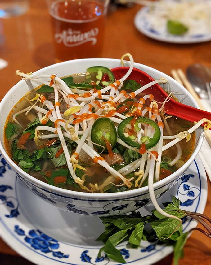 Steam rises from this bowl of pho like a fragrant invitation. Bean sprouts, jalapeños, and herbs stand ready for customization.