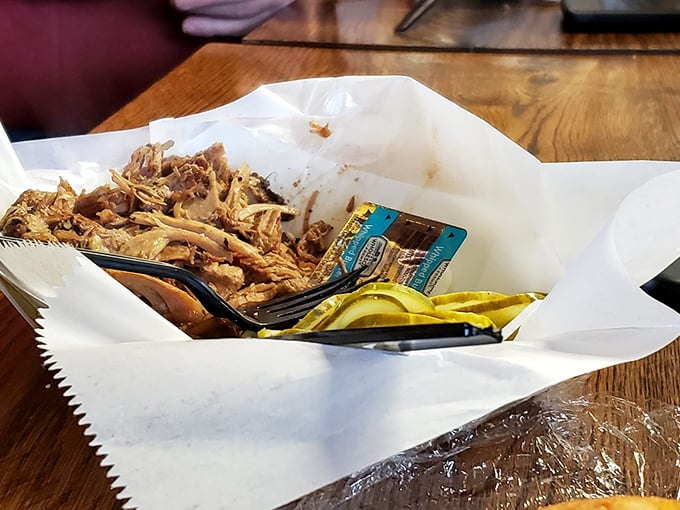 Behold the pork shoulder in all its glory—tender, pulled perfection nestled in butcher paper with pickle slices standing guard.