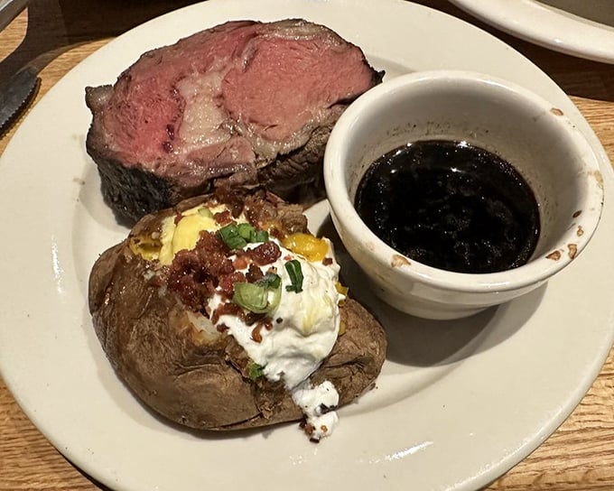 The star of the show: perfectly pink prime rib alongside a loaded baked potato and au jus. This isn't just dinner—it's a celebration on a plate.
