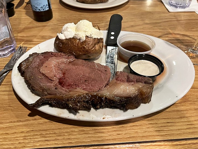 The prime rib arrives like a carnivore's dream—perfectly pink, accompanied by a loaded baked potato and savory au jus.