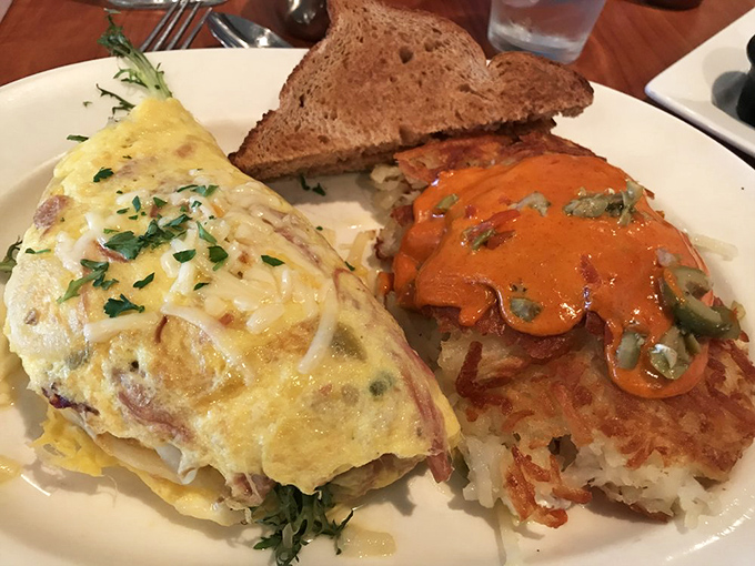 The legendary pulled ham omelet arrives like edible architecture—perfectly folded eggs cradling smoky ham, with those famous browns standing guard nearby.
