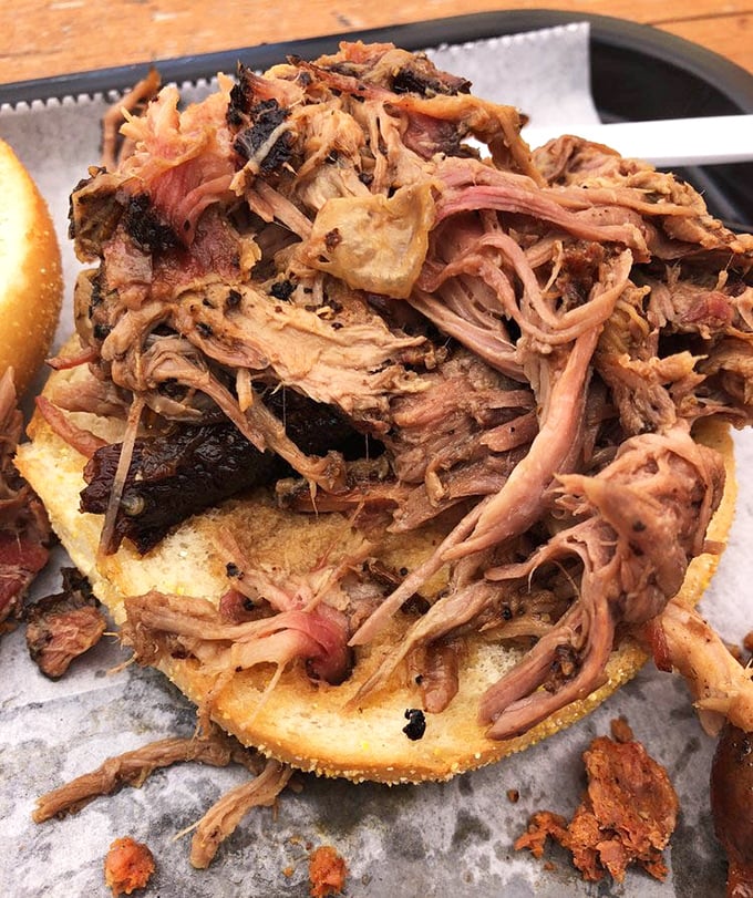 Pulled pork so tender it practically surrenders to gravity, piled high on a bun that's about to experience the greatest moment of its bread life.