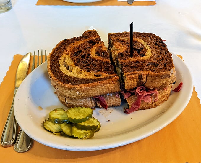 The legendary Reuben in all its glory—marble rye embracing corned beef in a warm hug while Swiss cheese plays matchmaker.