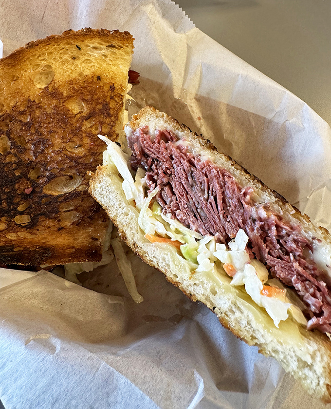 Behold the Reuben in its natural habitat – perfectly grilled rye embracing corned beef and sauerkraut in a dance as old as delicatessens themselves.