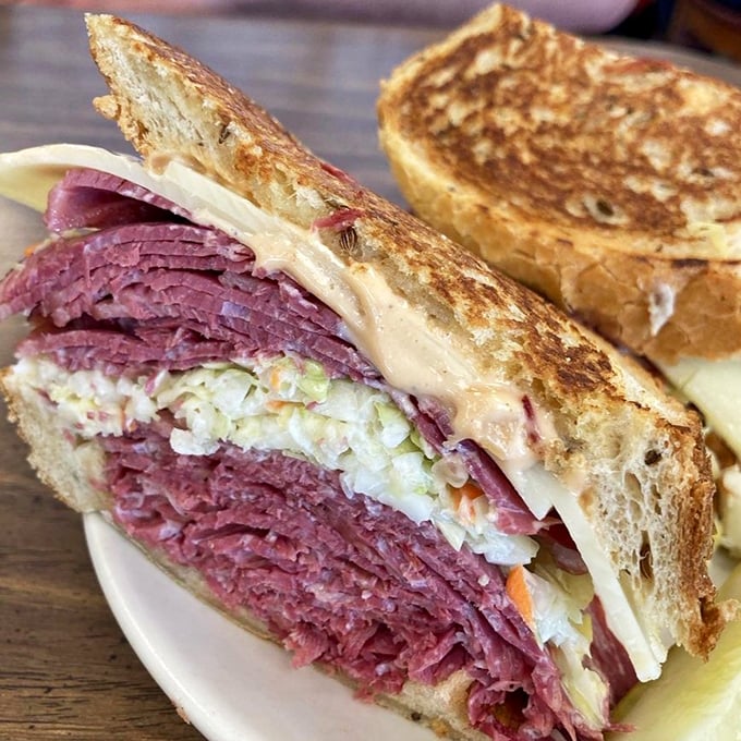 Behold the Reuben in its natural habitat – a mountain of corned beef that requires both hands and possibly a building permit.