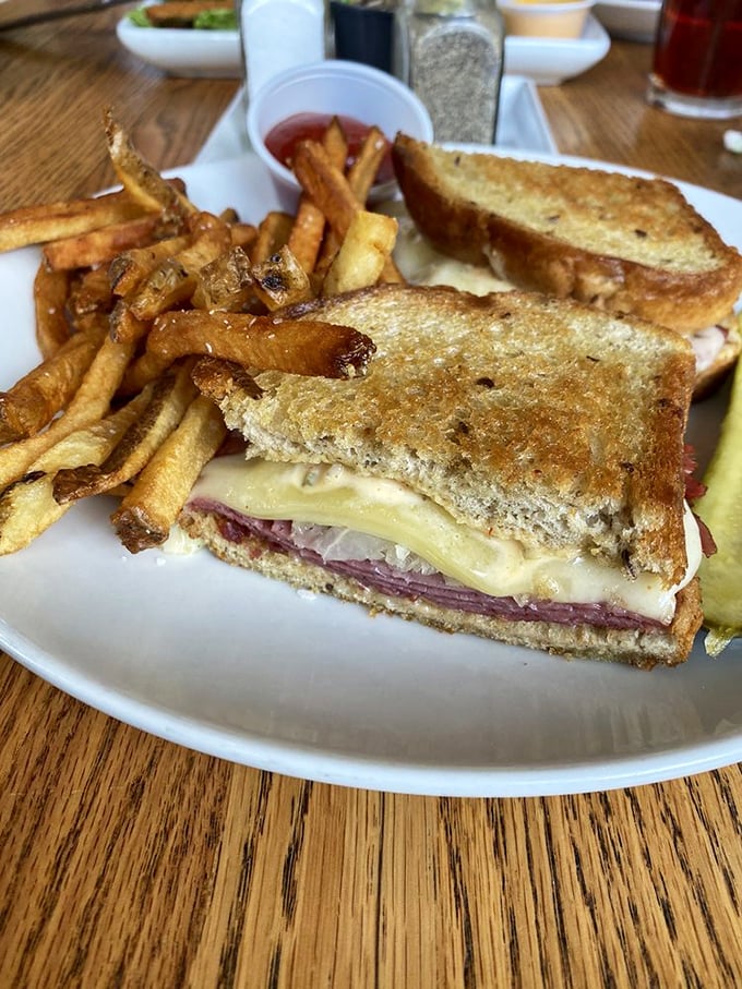 The Reuben arrives like a work of art—perfectly grilled rye embracing corned beef, Swiss, and sauerkraut with hand-cut fries standing guard.