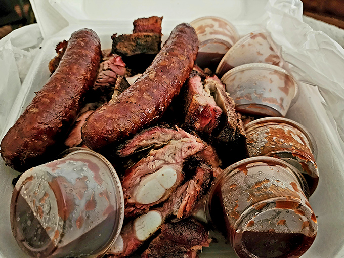 Behold the holy grail of barbecue—rib tips with that perfect bark, nestled alongside sauce cups like treasures. This is what barbecue dreams are made of.