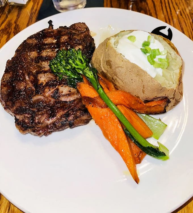 A perfectly charred ribeye with that textbook crosshatch pattern, loaded baked potato, and vibrant vegetables. This isn't dinner – it's edible artwork.