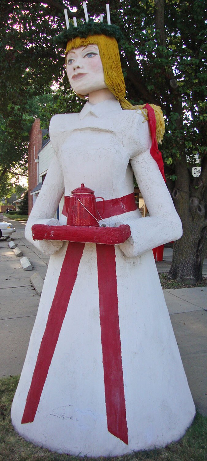 Saint Lucia stands sentinel in her traditional white gown, coffee pot in hand – because even Swedish traditions understand caffeine is non-negotiable.