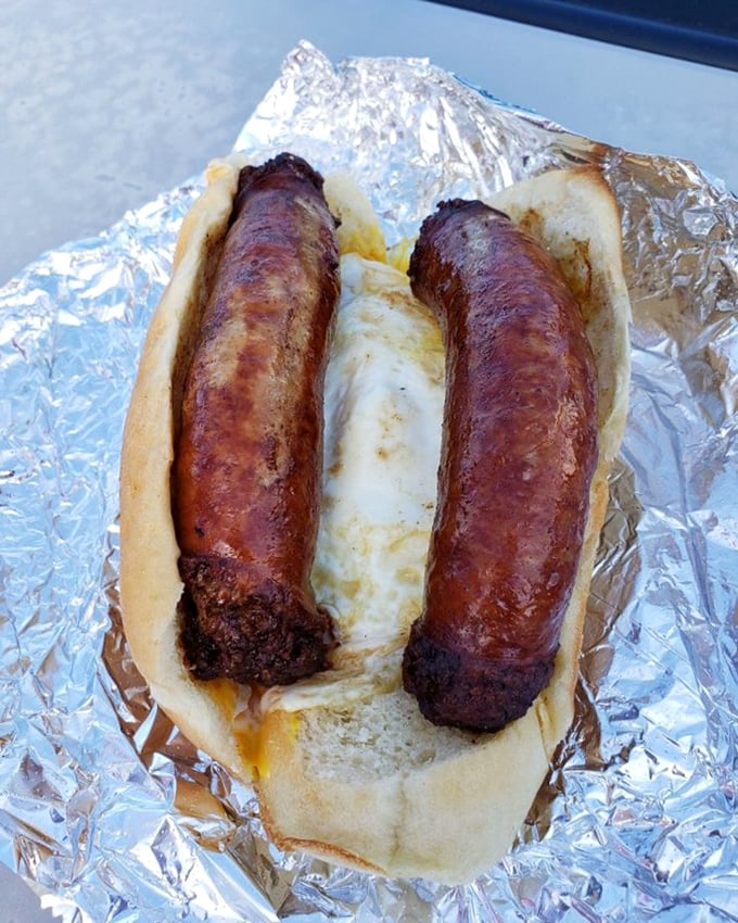 Behold the star attraction – two plump sausages nestled in a soft roll. Poetry in pork form that's worth every mile of the journey.