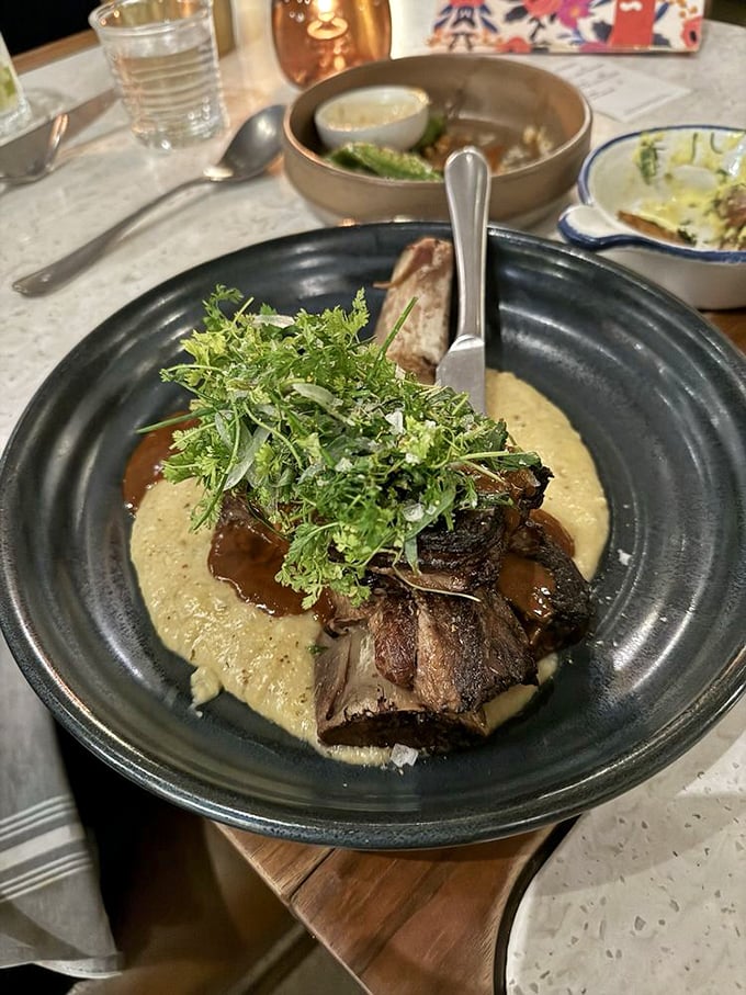 Behold the legendary short rib, resting on a cloud of polenta like a meaty meteor that crashed into flavor heaven. The microgreens aren't just garnish—they're the victory flag.