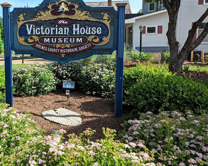The sign says "Victorian House Museum" but might as well read "Time Portal: 1890s Edition." The Holmes County Historical Society keeps history blooming as vibrantly as those flowers.