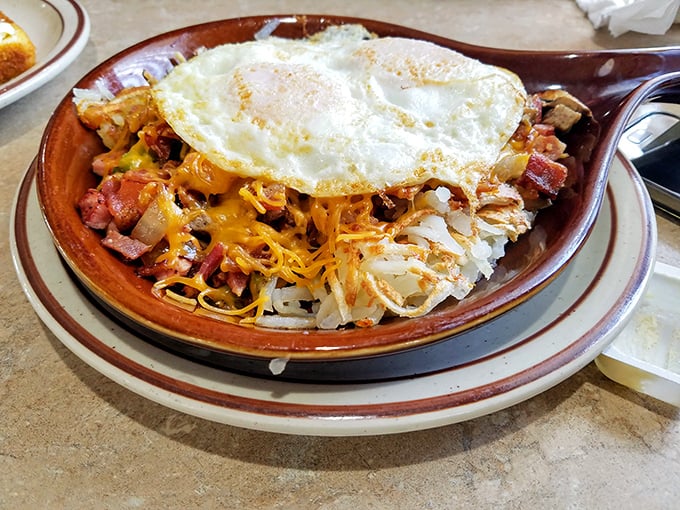Behold the breakfast skillet—where hash browns, eggs, and various breakfast meats hold their morning summit conference under a melty cheese canopy.