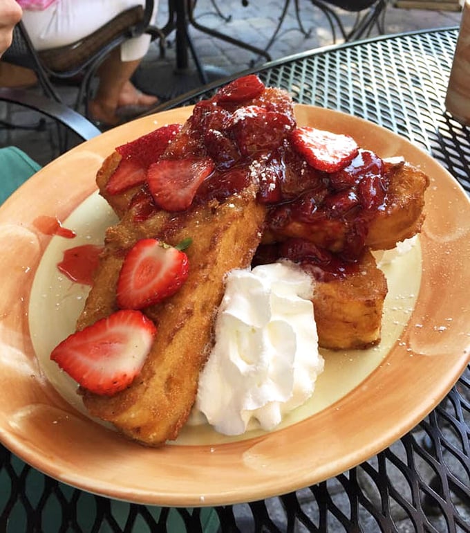 The French toast that launched a thousand return visits – golden, custardy perfection crowned with fresh strawberries and a cloud of whipped cream.
